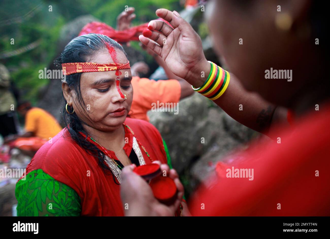 A Hindu devotee applies vermilion powder on her friends forehead during ...