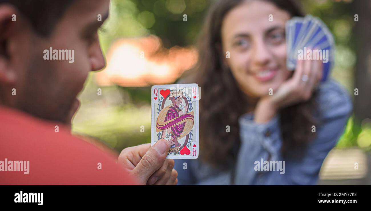 Card playing in a spring garden: Couple are sitting on a table ...