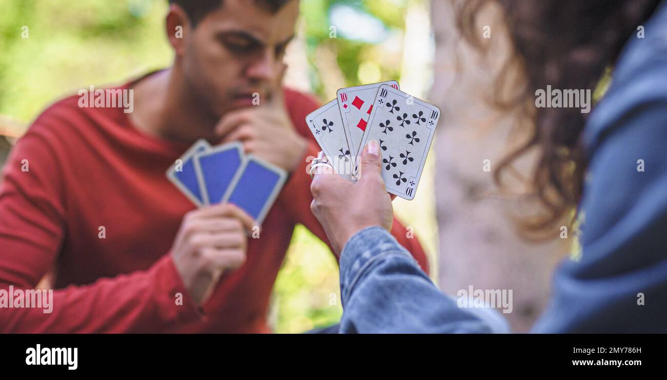 Card playing in a spring garden: Couple are sitting on a table ...