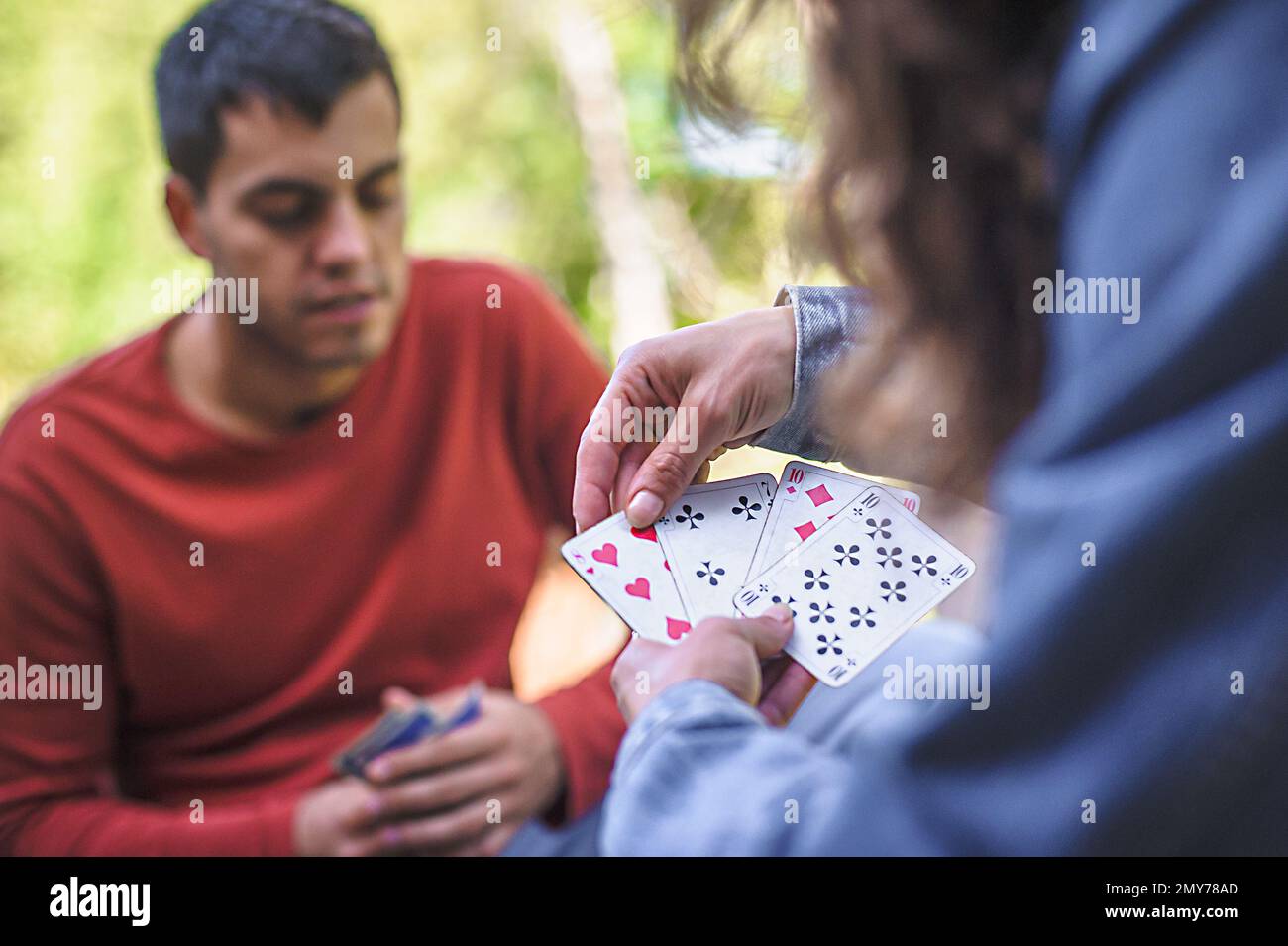 Card playing in a spring garden: Couple are sitting on a table ...