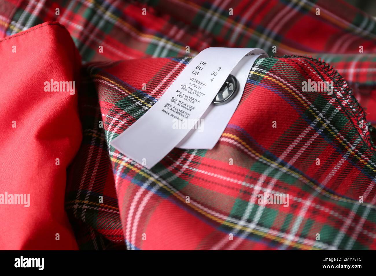 Clothing label with size and content information on red plaid garment ...