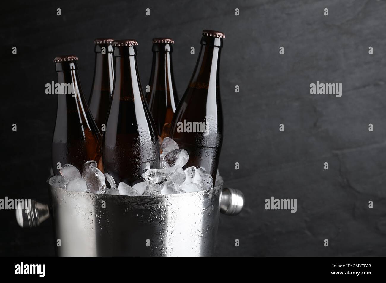 Metal bucket with beer and ice cubes on black background, closeup ...