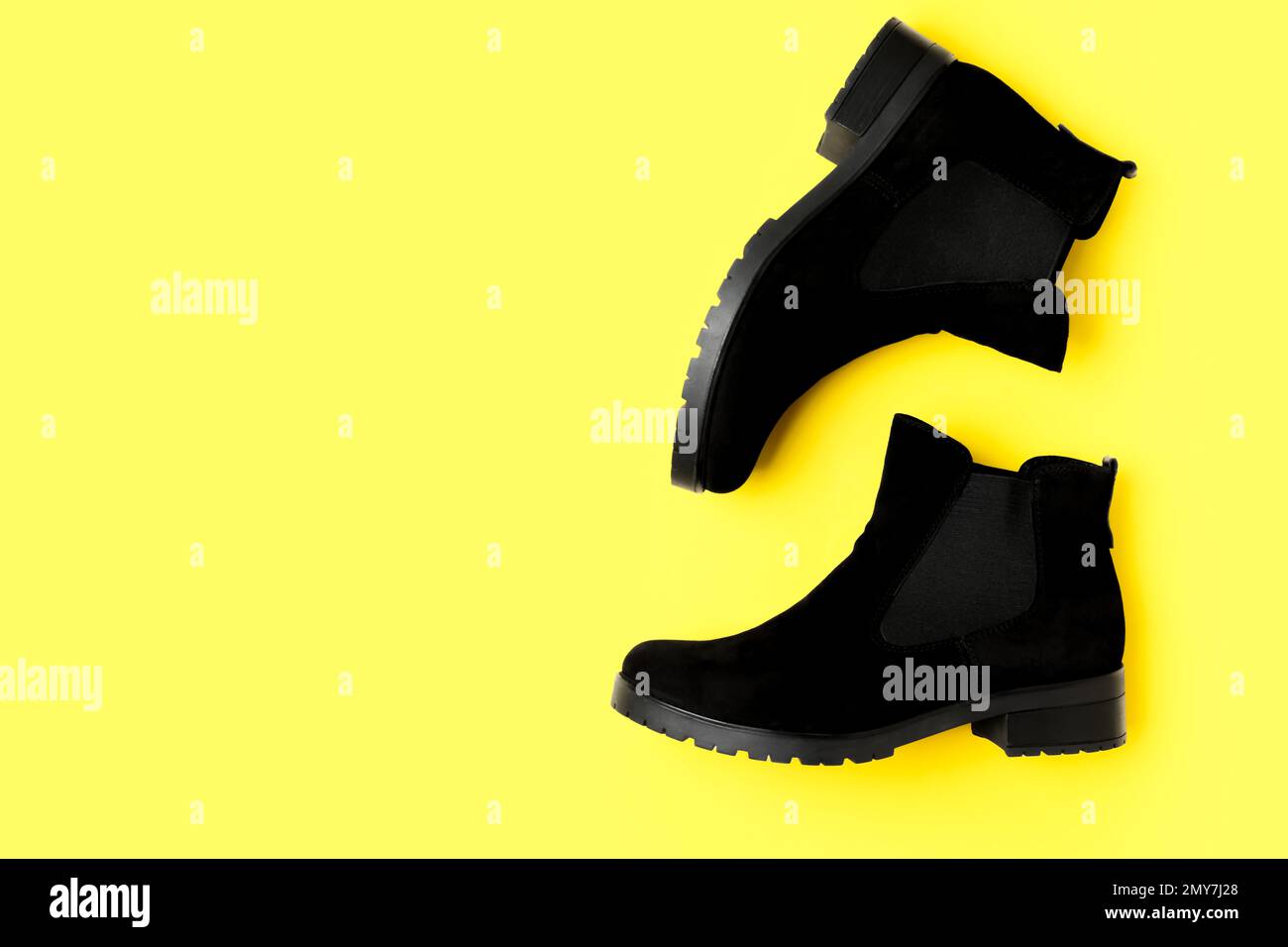 Stylish black female boots on yellow background, flat lay. Space for ...
