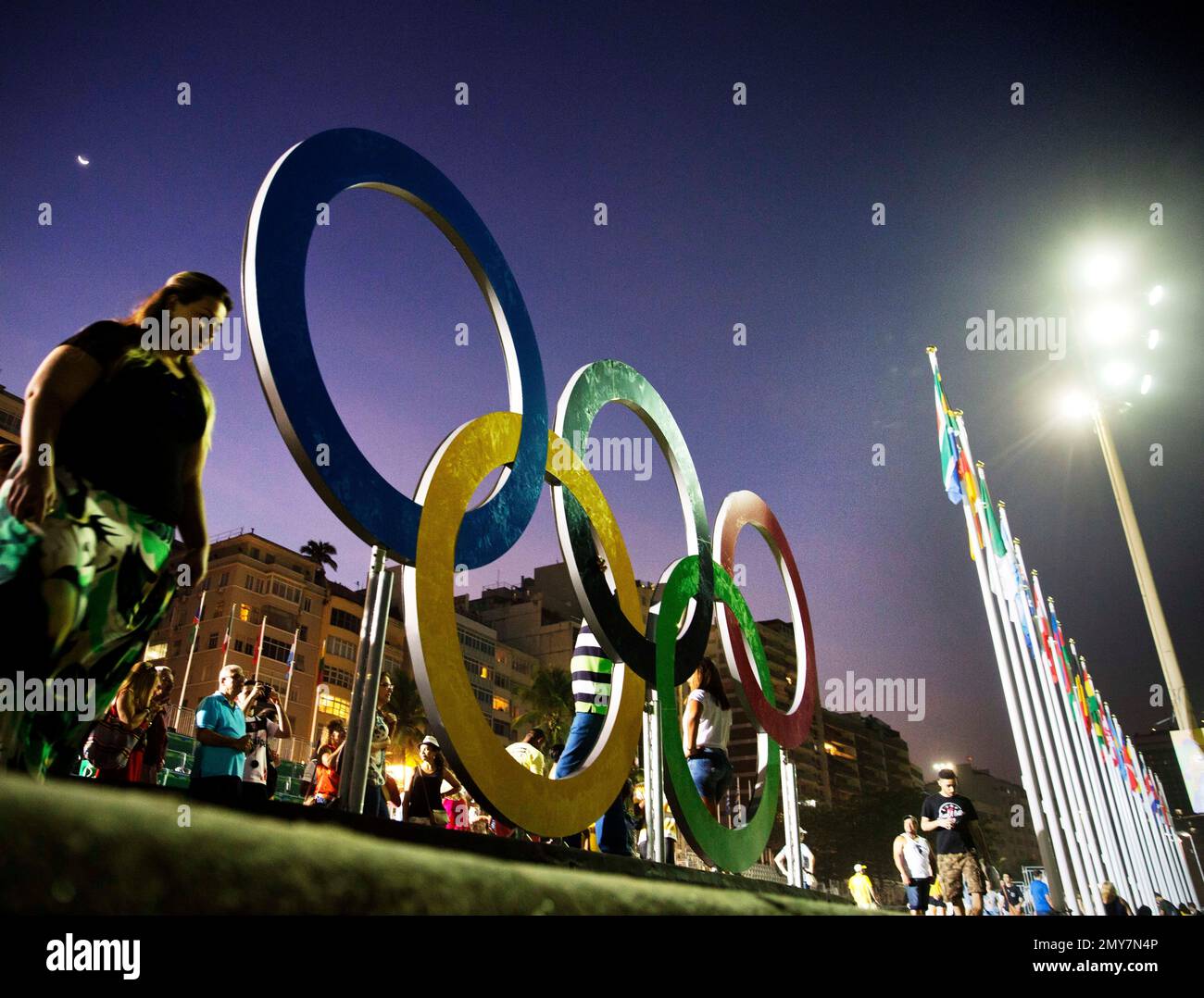 Pedestrians pass by the Olympic rings along Copacabana beach, site of ...