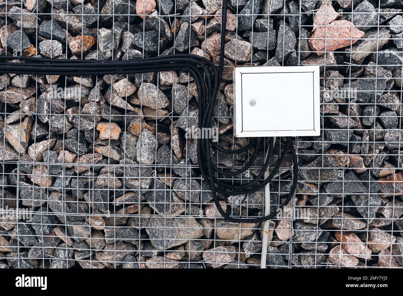 A transformer box with wires hangs on a stone fence. Energy. Power ...
