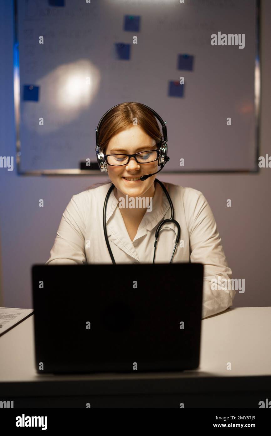 Hotline in hospital. Smiling female doctor in white coat in headset ...