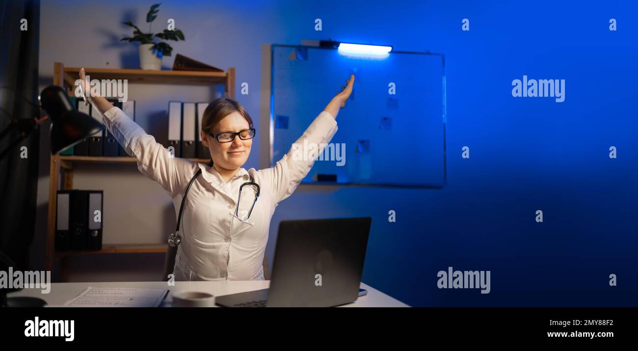 Doctor staying late on hospital at night shift, stretching sitting at ...