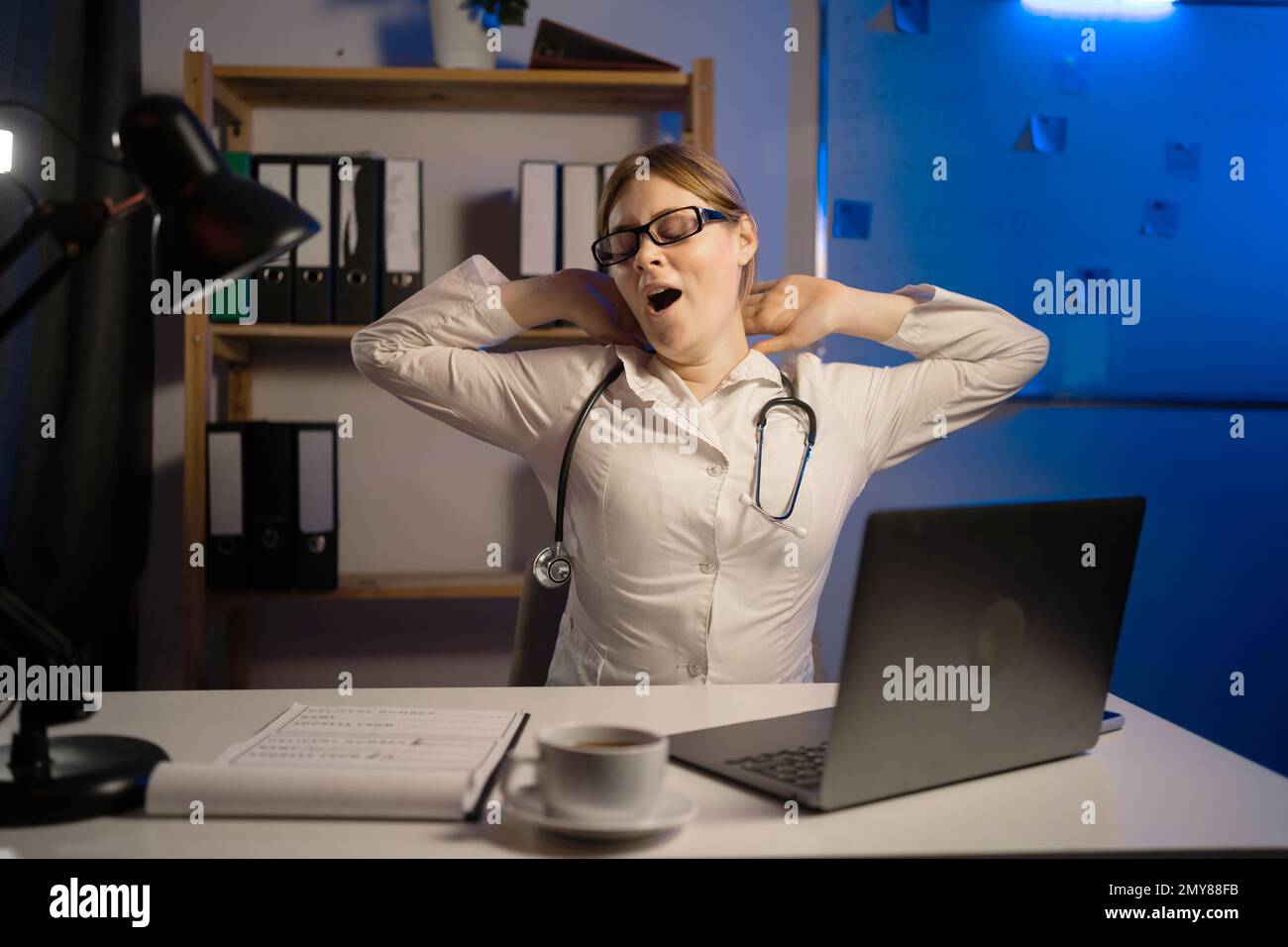 Tired medical doctor woman yawning in office duty at night Stock Photo ...