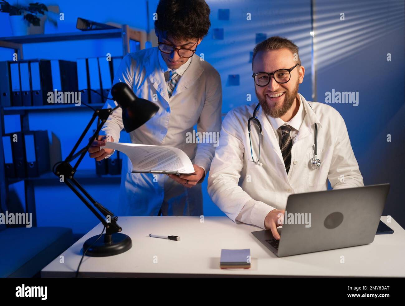Two doctors colleagues working at hospital office at night shift ...