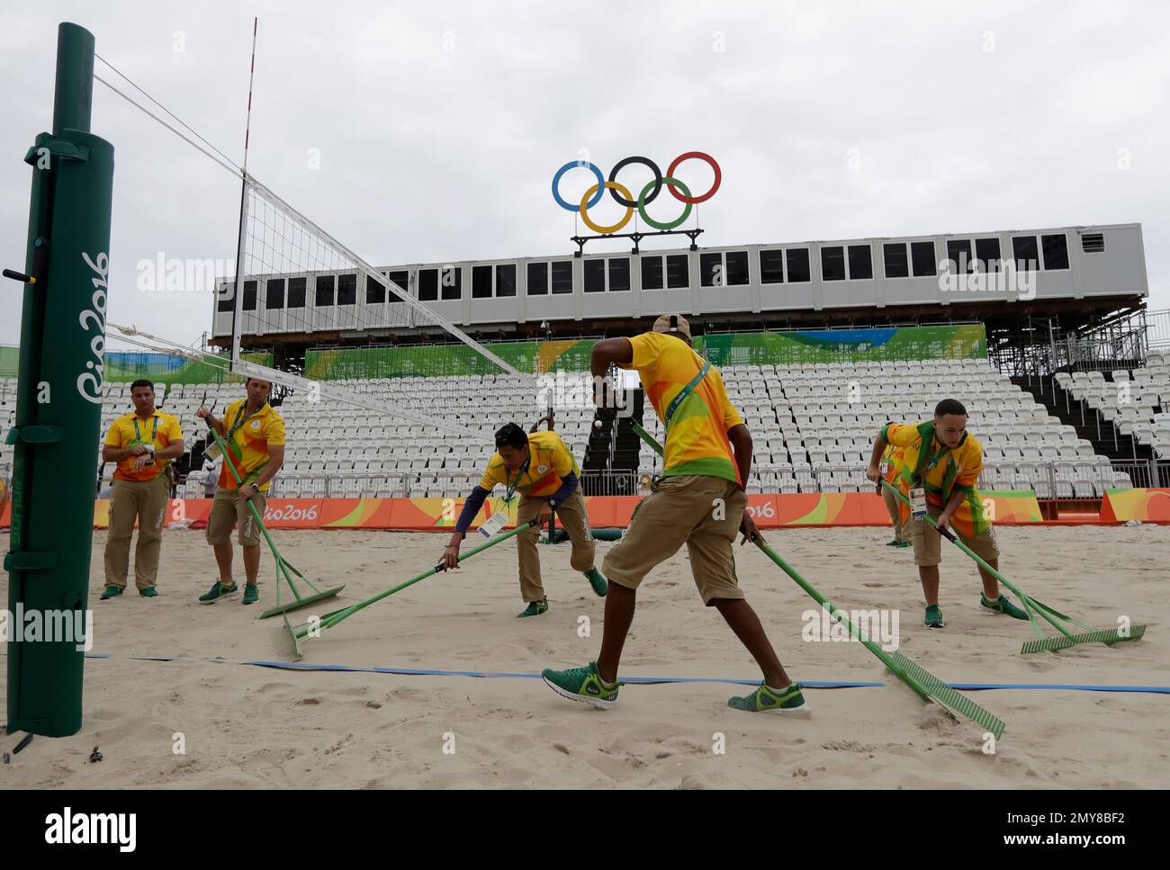 Volunteers rake the field of play at the Copacabana beach volleyball ...