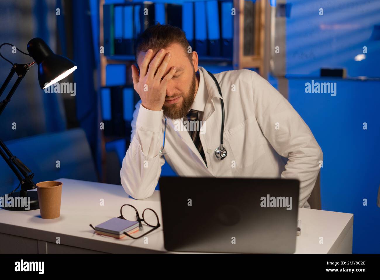 Male tired doctor with migraine overworked, overstressed working at ...