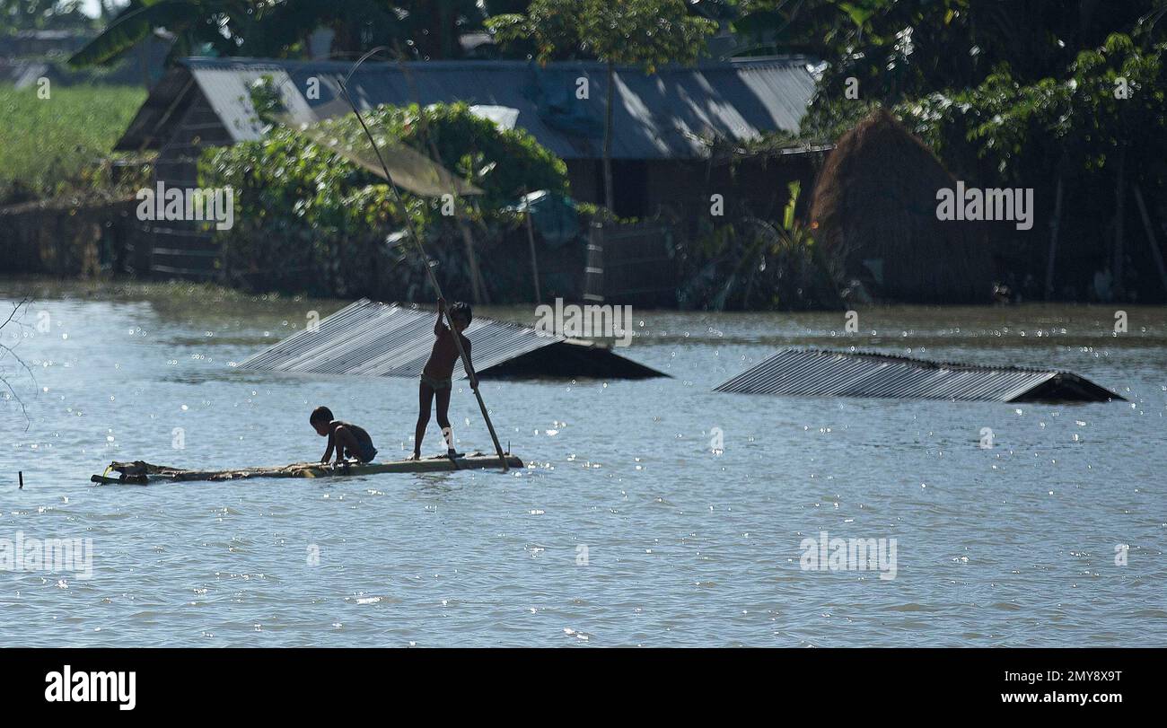 Flood affected children on a banana raft move past submerged huts in ...
