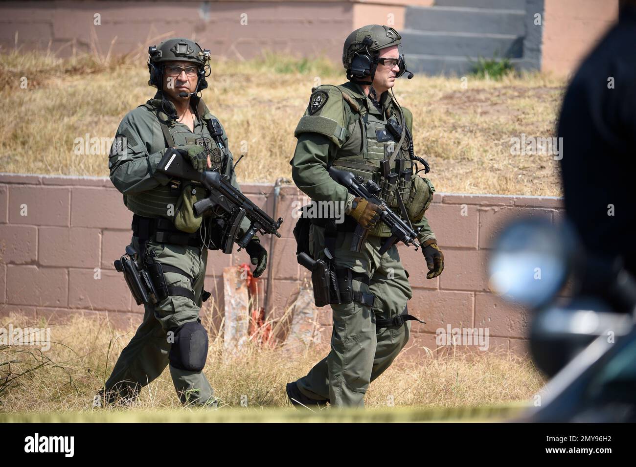 San Diego Police SWAT officers walk around to the back side of a house ...