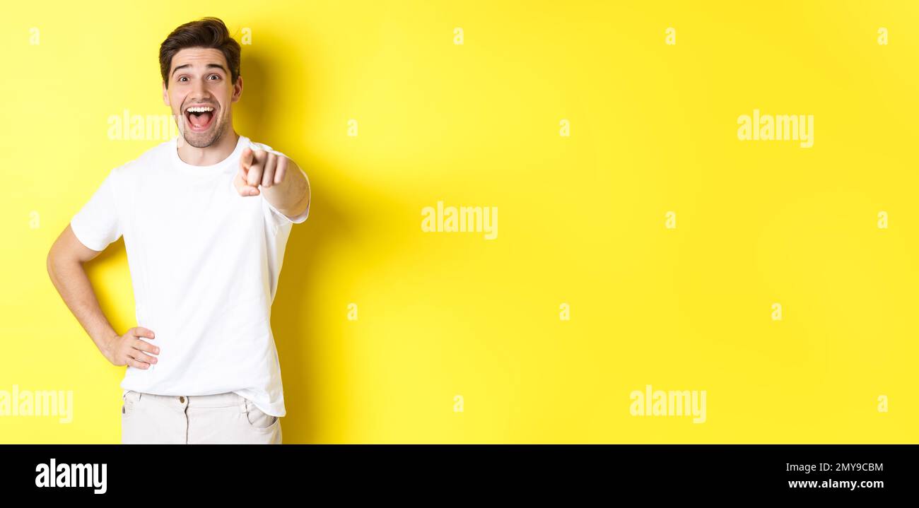 Happy guy pointing finger at camera and laughing, check out something ...