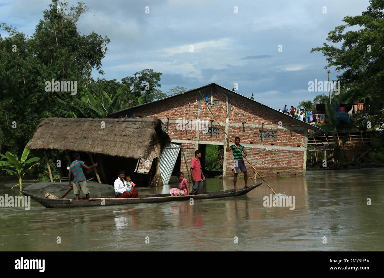 A flood affected family moves on a boat past partially submerged houses ...