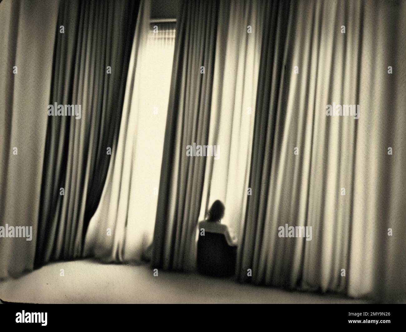 A woman sitting at the window looking contemplative and thoughtful ...