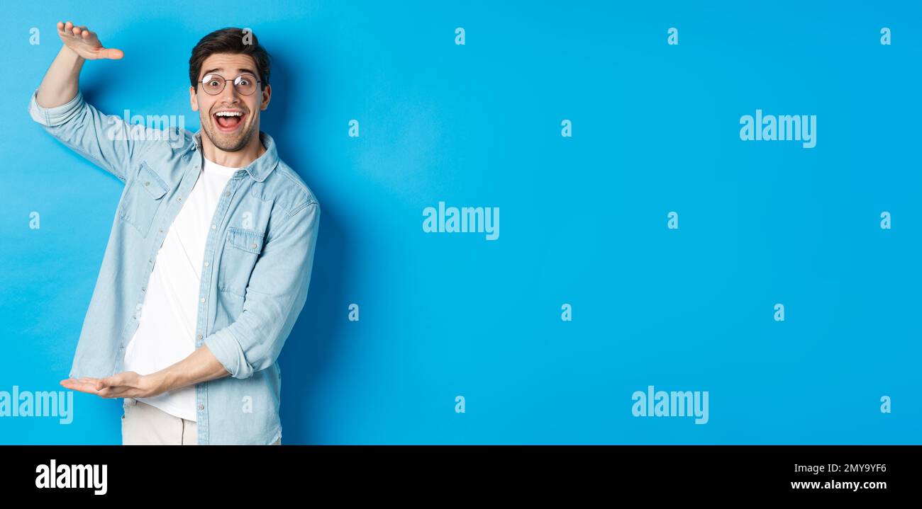 Happy man in glasses showing big size object, shaping large box ...