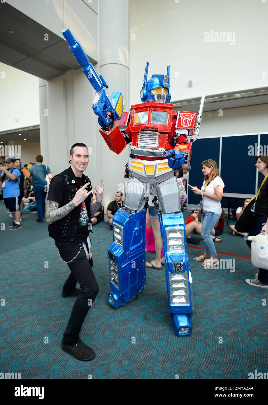 A fan poses with a giant Transformer in the convention center on day ...