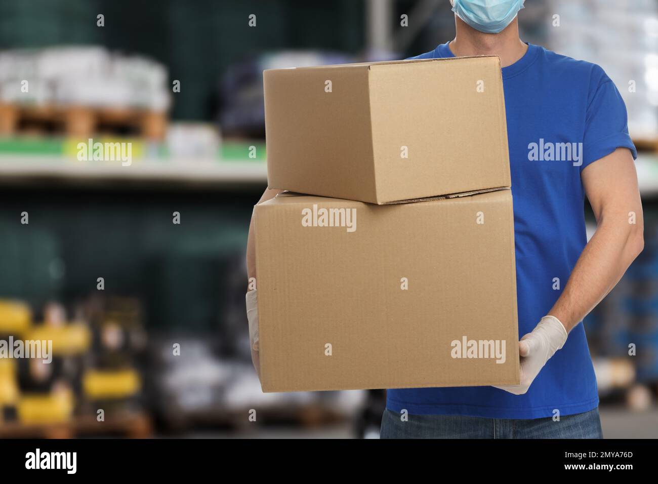 Man wearing uniform and medical mask with cardboard boxes in store ...