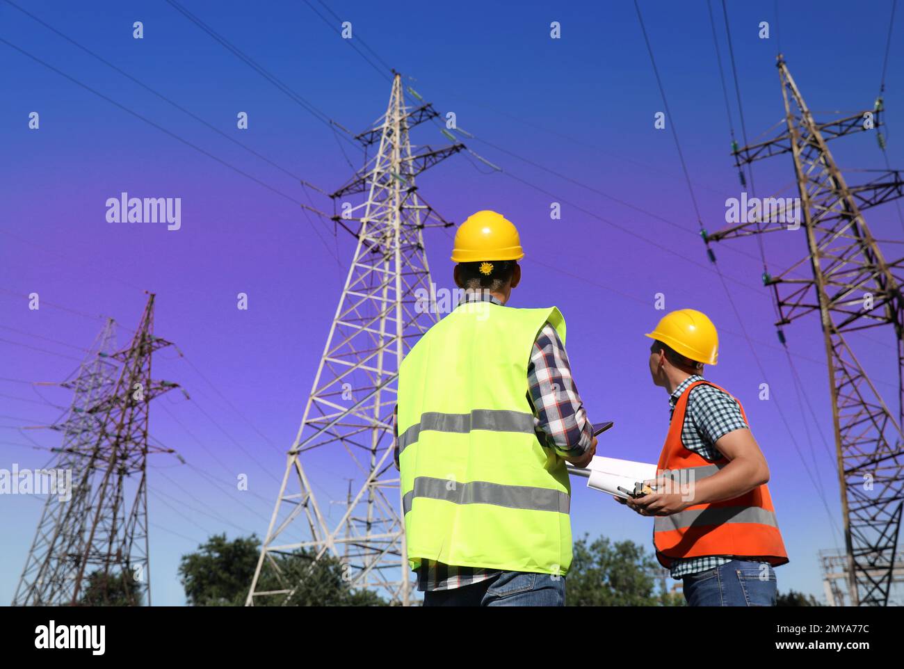 Professional electricians in uniforms near high voltage towers Stock ...