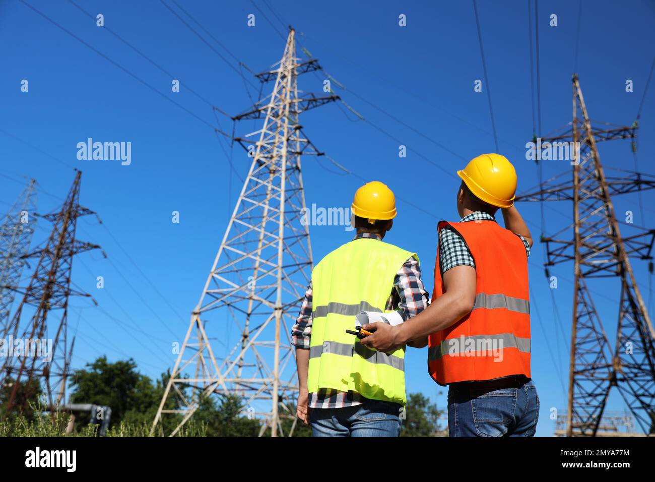 Professional electricians in uniforms near high voltage towers Stock ...