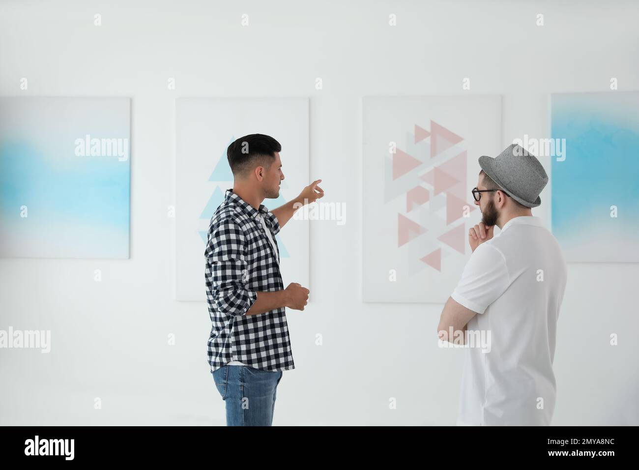 Men discussing artworks at exhibition in art gallery Stock Photo - Alamy