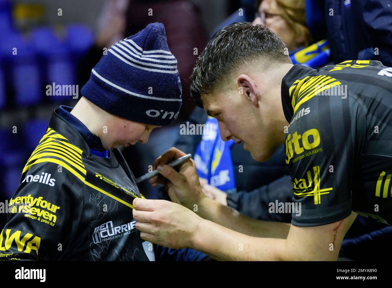 Josh Thewlis #2 of Warrington Wolves signs the shirt of a young fan ...