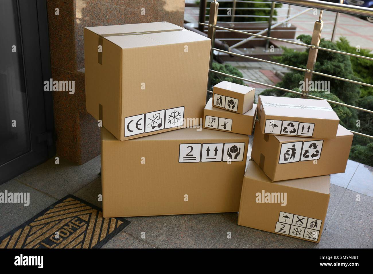 Cardboard boxes with different packaging symbols on porch near entrance ...