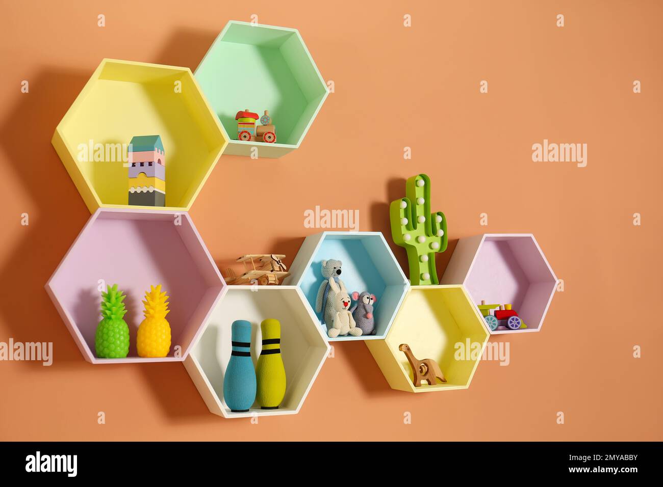 Hexagon shaped shelves with toys on orange wall. Interior design Stock ...
