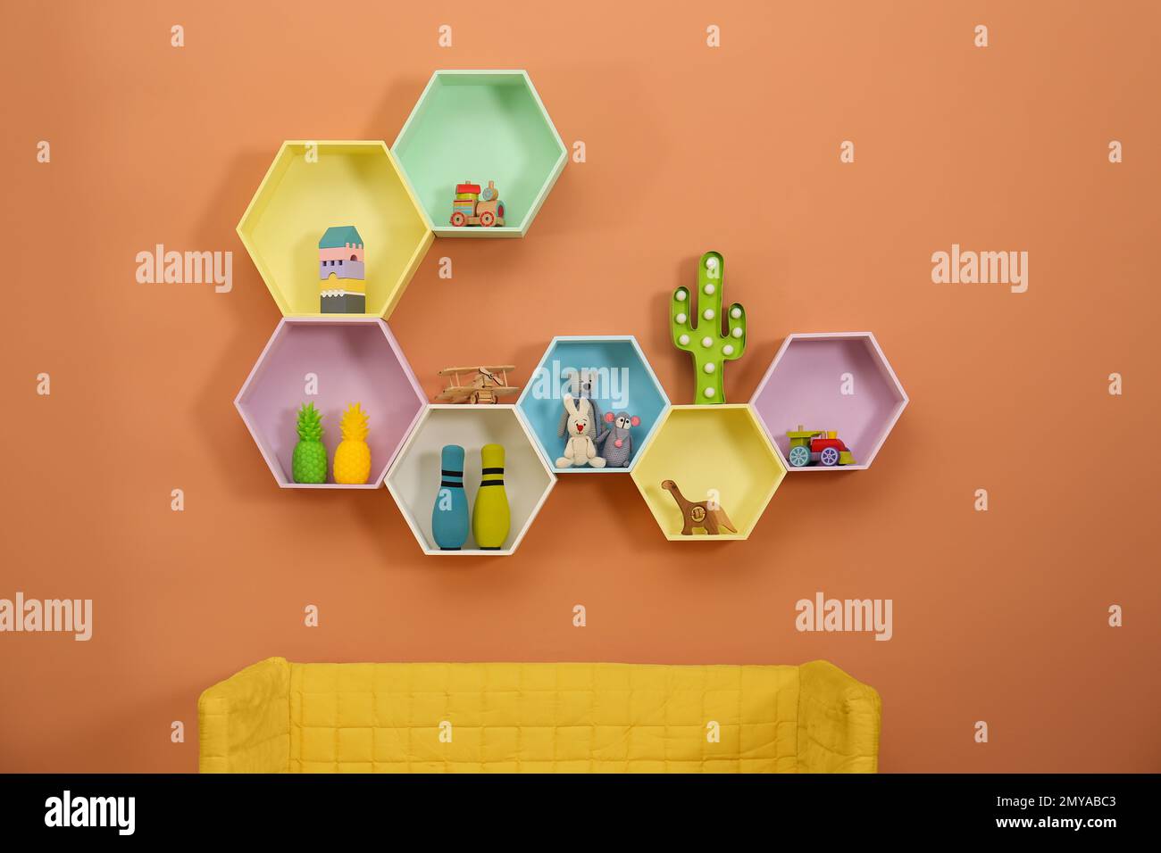 Sofa near orange wall with hexagon shaped shelves in room. Interior ...