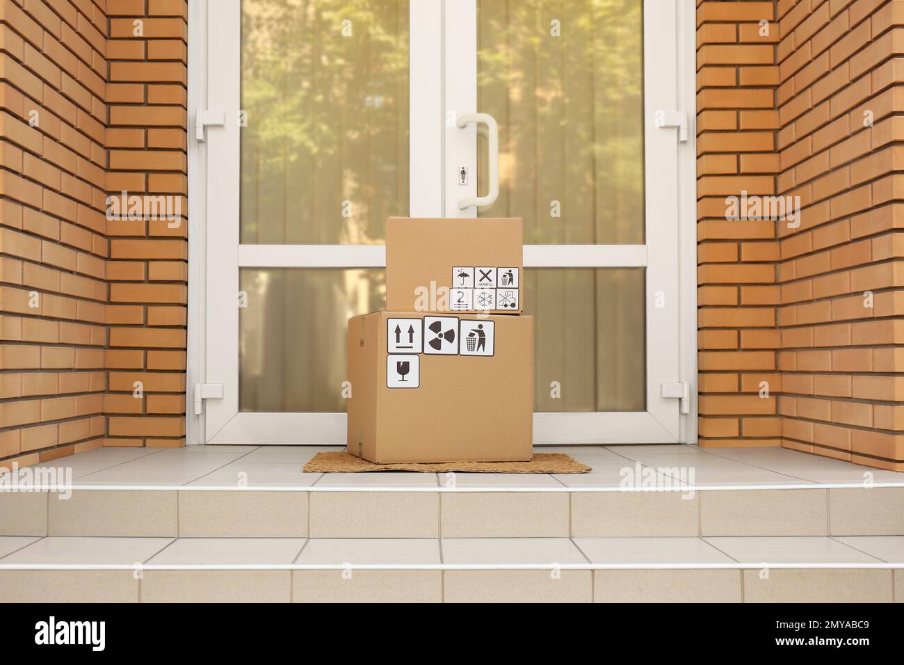 Cardboard boxes with different packaging symbols on door mat near ...