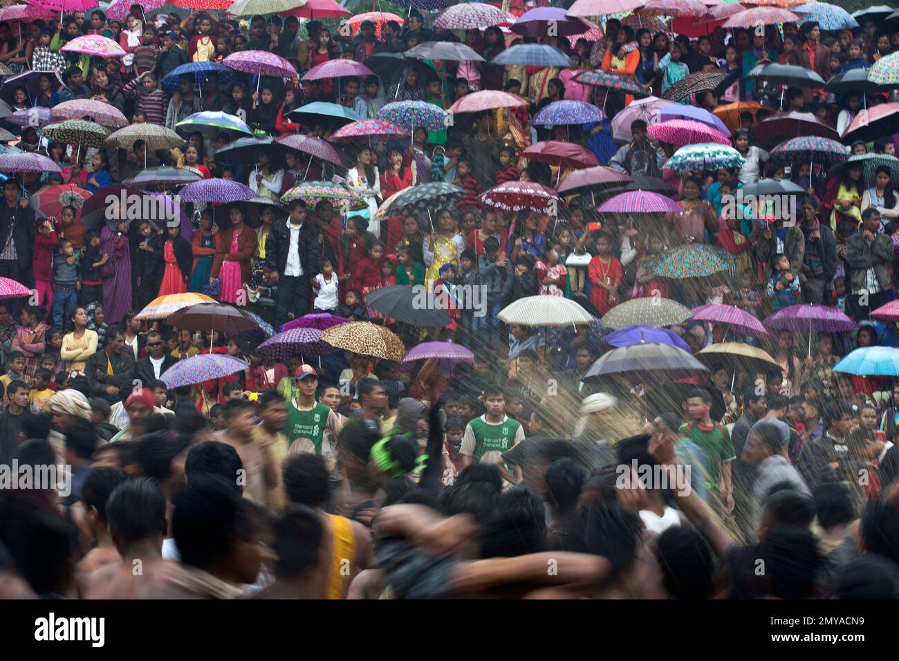 Indian Pnar or Jaintia tribesmen dance in muddy waters, as others hold ...