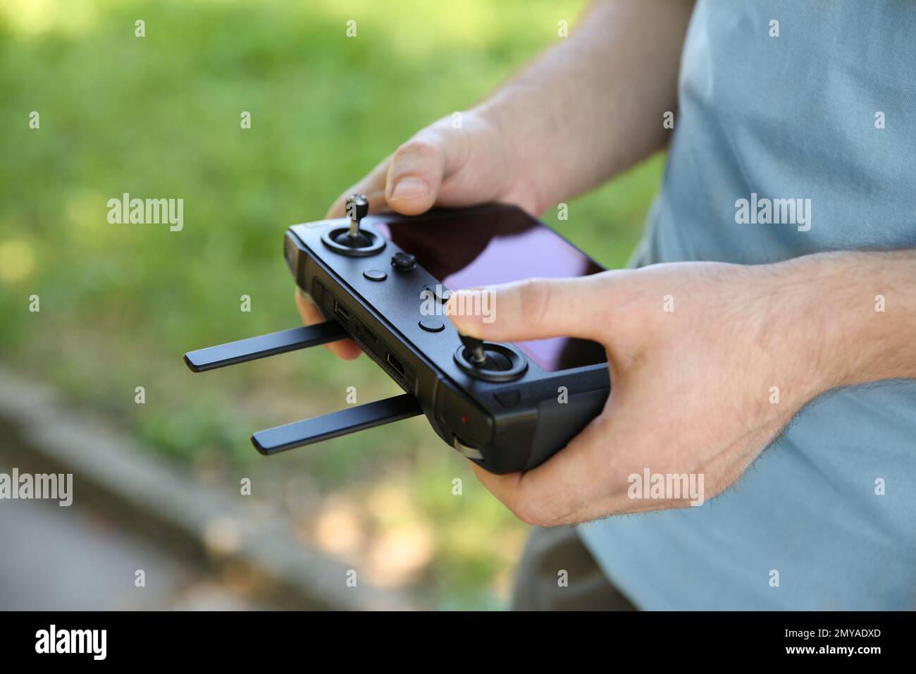Man holding new modern drone controller outdoors, closeup of hands ...