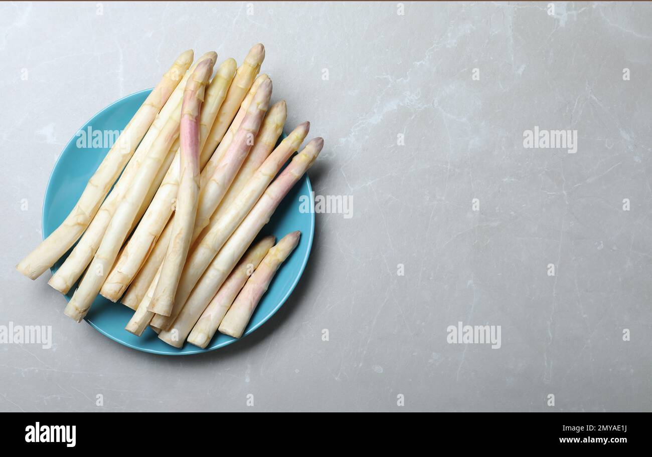 Fresh white asparagus on grey marble table, top view. Space for text ...