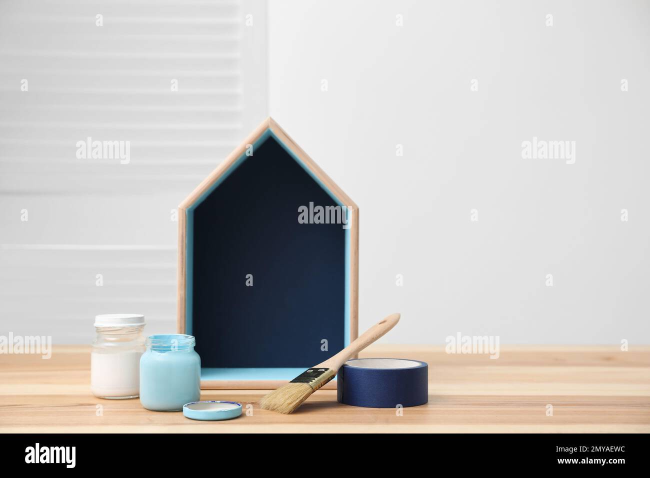 House shaped shelf, jars of paints and decorator tools on table. Space ...