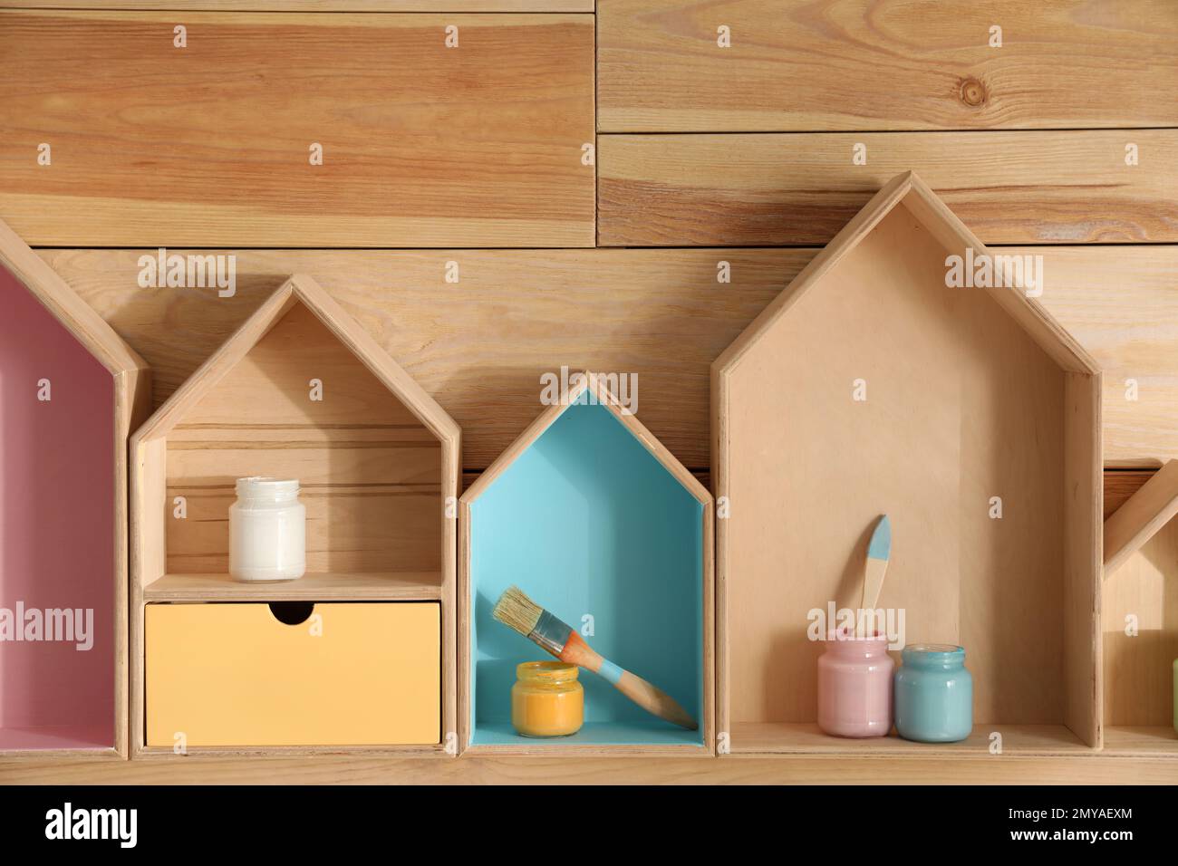 House shaped shelves with jars of paints and brushes on wooden wall ...