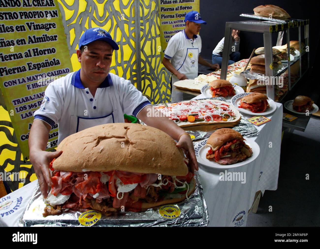A cook arranges the top bun on a giant torta, or sandwich, during a ...