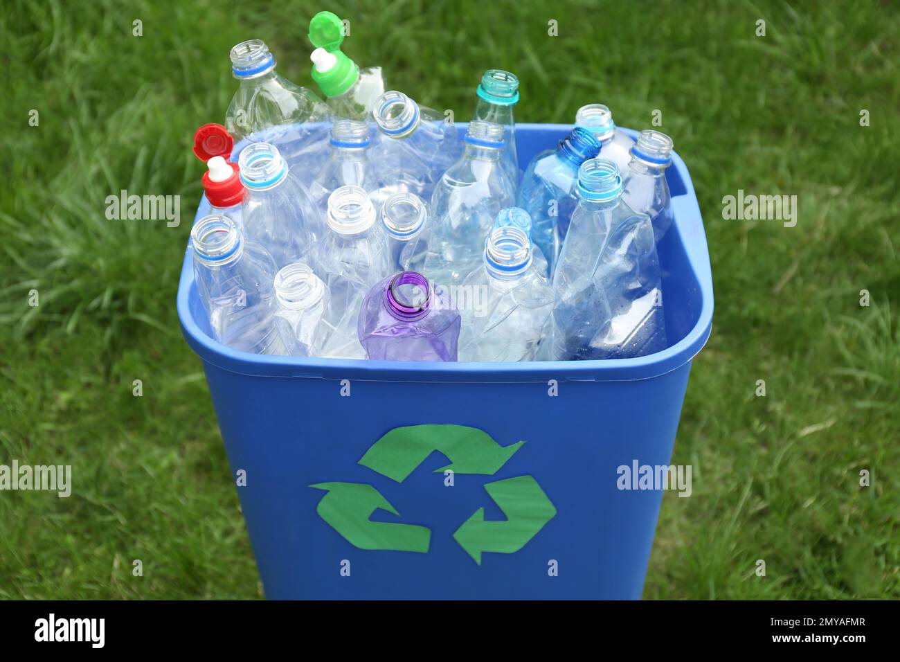 Many used bottles in trash bin outdoors, closeup. Plastic recycling ...