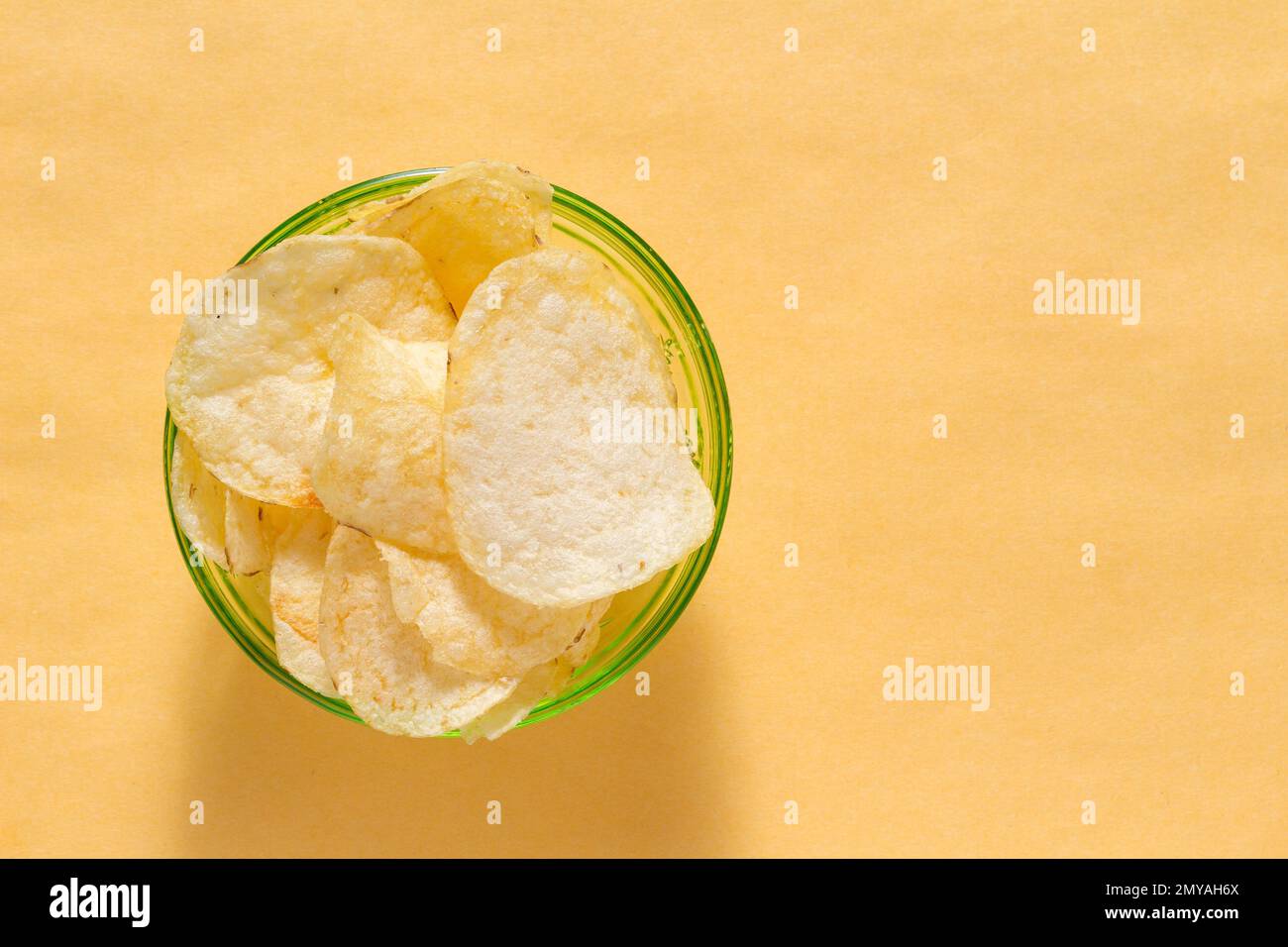 Lots of potato chips in container on yellow background Stock Photo - Alamy