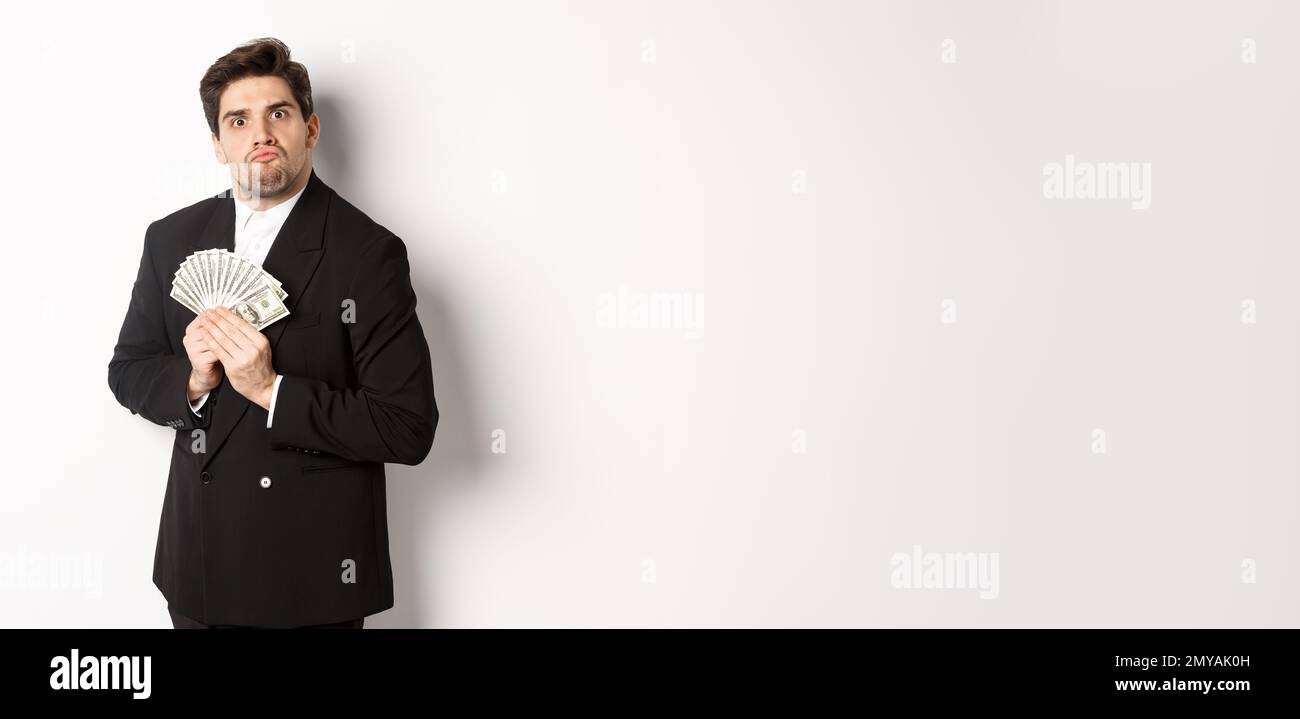 Image of greedy guy in black suit, holding money and unwilling to share ...