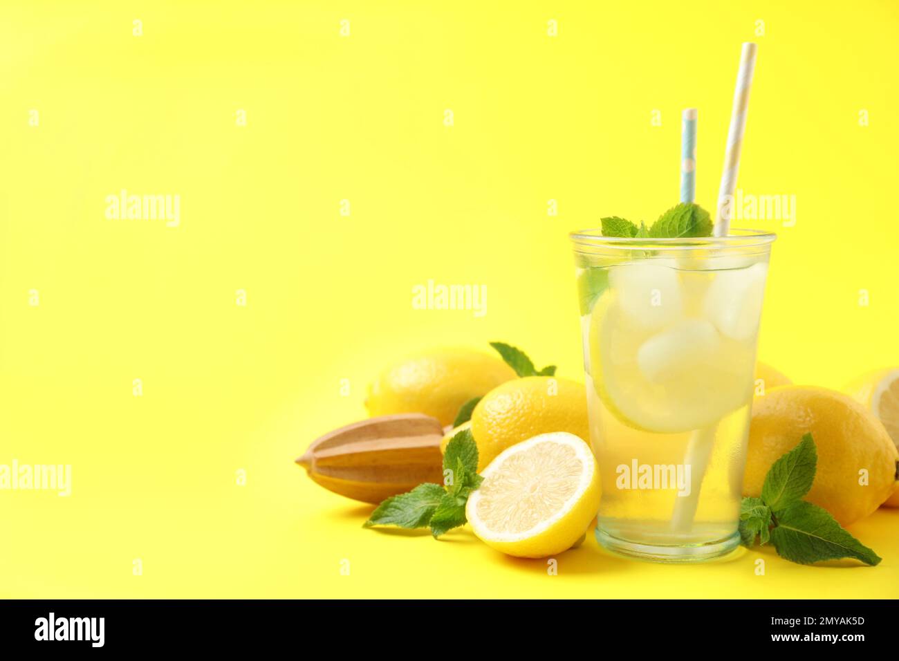 Natural freshly made lemonade with squeezer on yellow background, space ...
