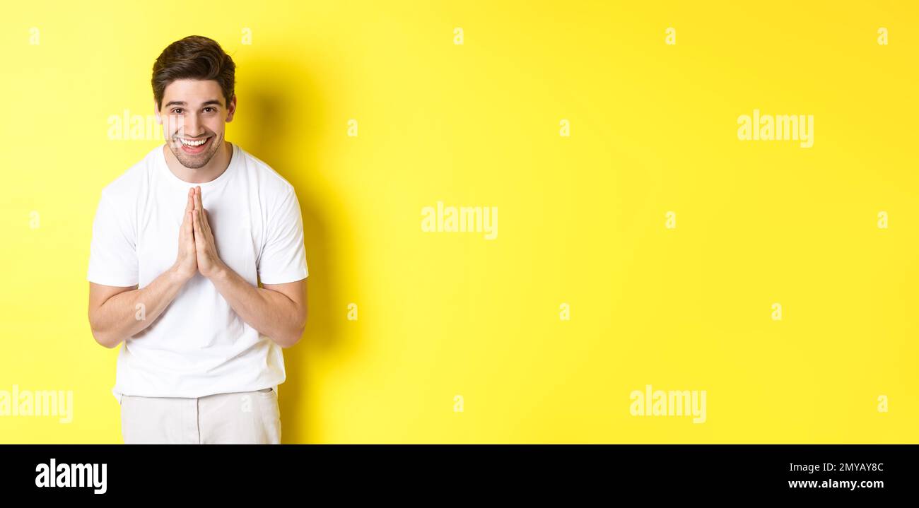 Handsome guy saying thank you, bowing and holding hands in namaste ...