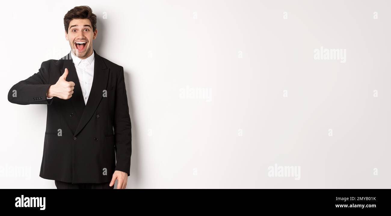 Portrait of amazed and impressed handsome man in black suit, showing ...