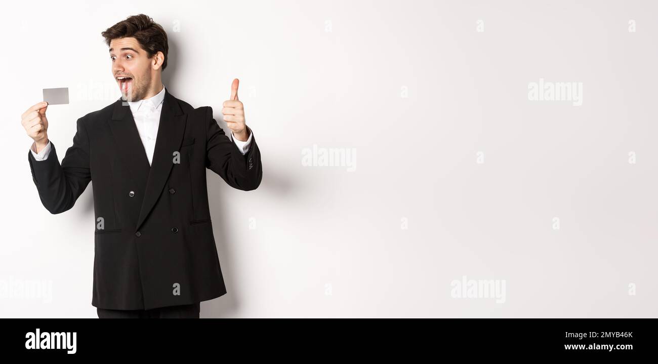 Image of excited handsome businessman, showing credit card and thumb-up ...