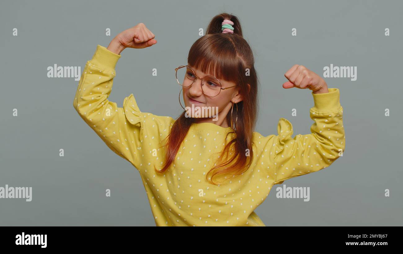 I am strong and healthy. Young toddler girl in glasses showing biceps ...