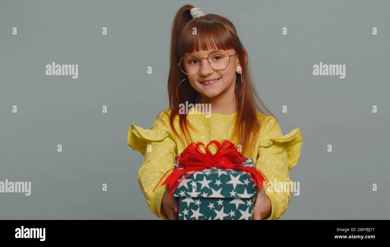 Lovely smiling young preteen child girl kid presenting birthday gift ...