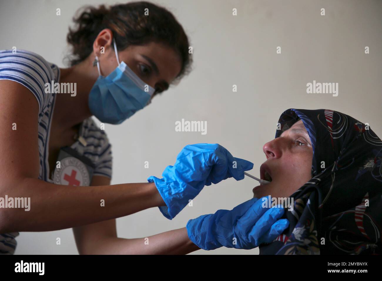 A member of The International Red Cross takes a saliva sample from ...