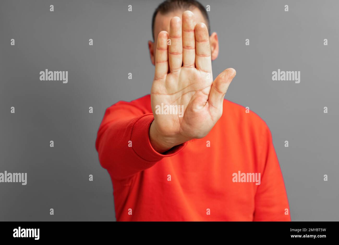 Hispanic man putting hand in front to stop camera, rejecting photos or ...