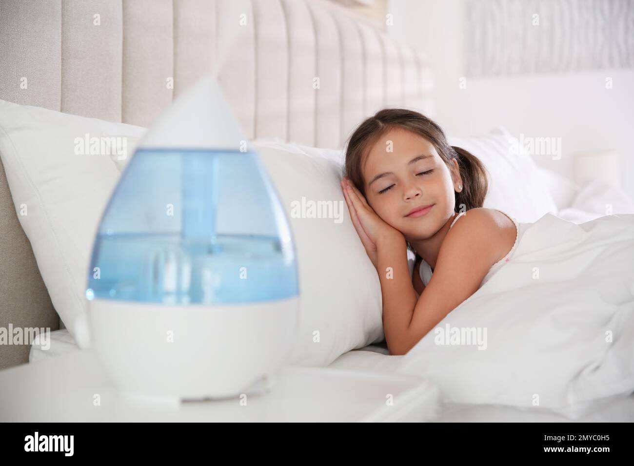 Cute little girl sleeping in bedroom with modern air humidifier Stock ...
