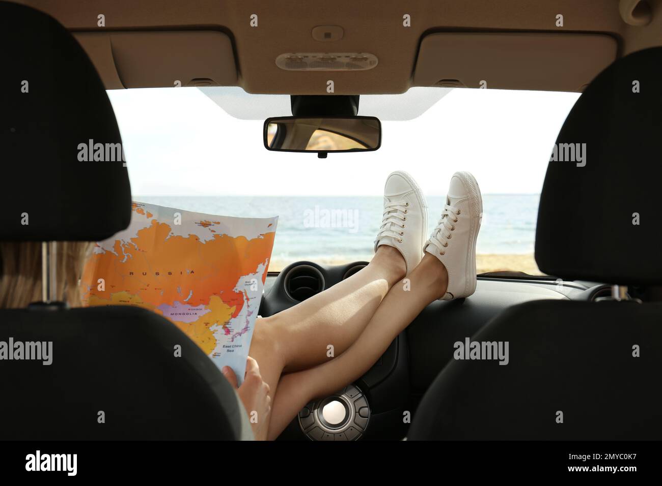 Young woman with world map in car, back view. Road trip Stock Photo - Alamy